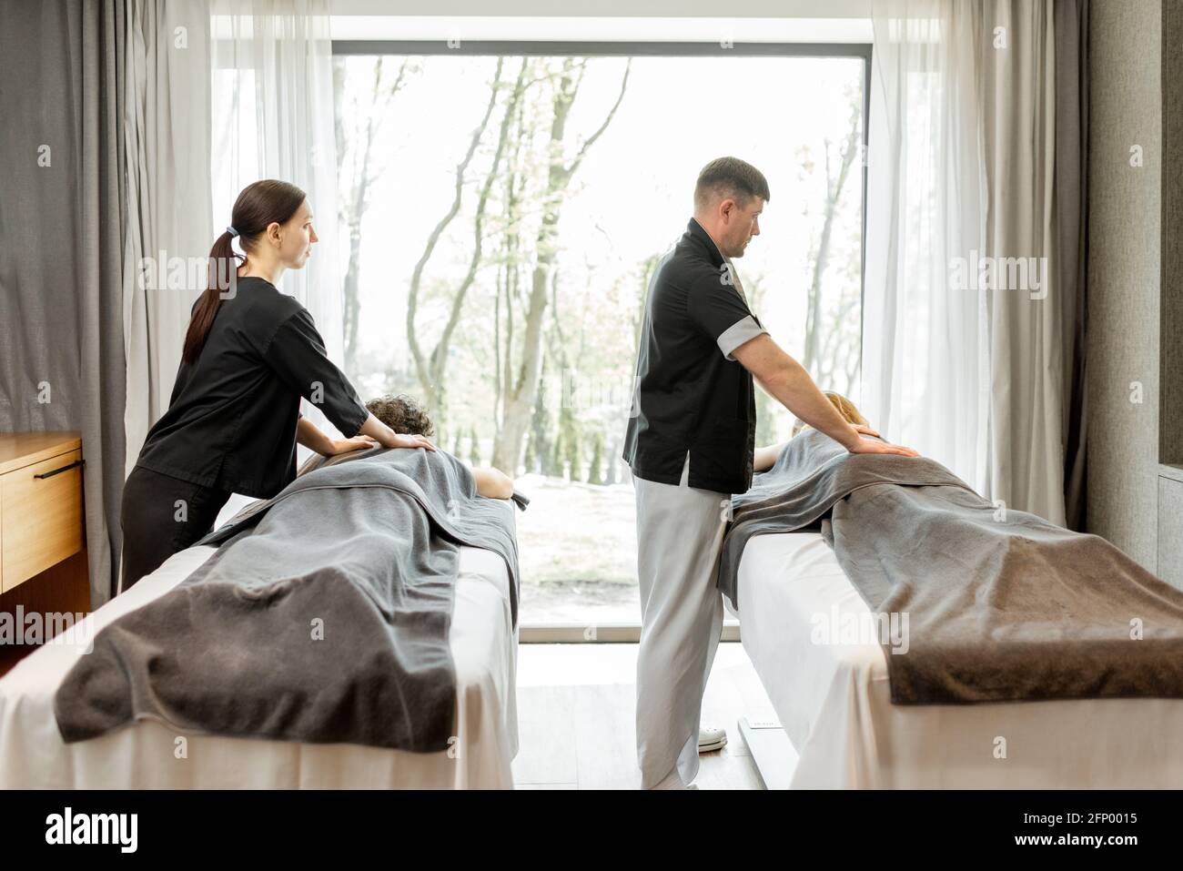 Two masseurs doing a deep back massage to guests with pampering ...