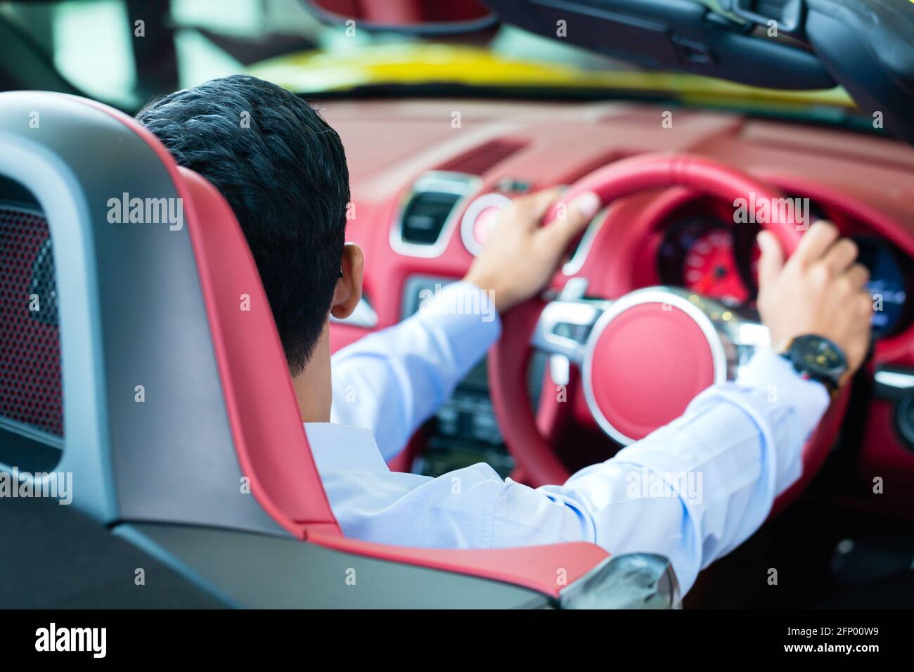 Asian man testing new sports car at car dealership Stock Photo - Alamy