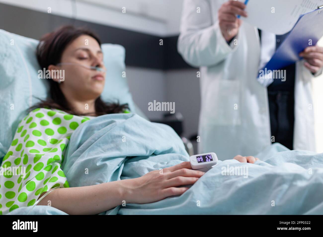 Close up of sick woman resting in bed with finger heart rate monitor ...