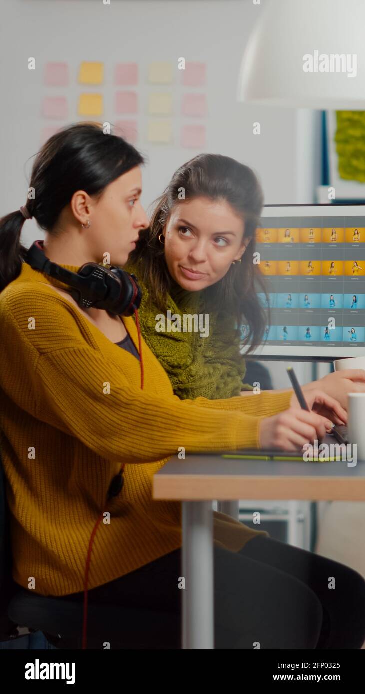 Confident women photo editors sitting at workplace in creative studio ...