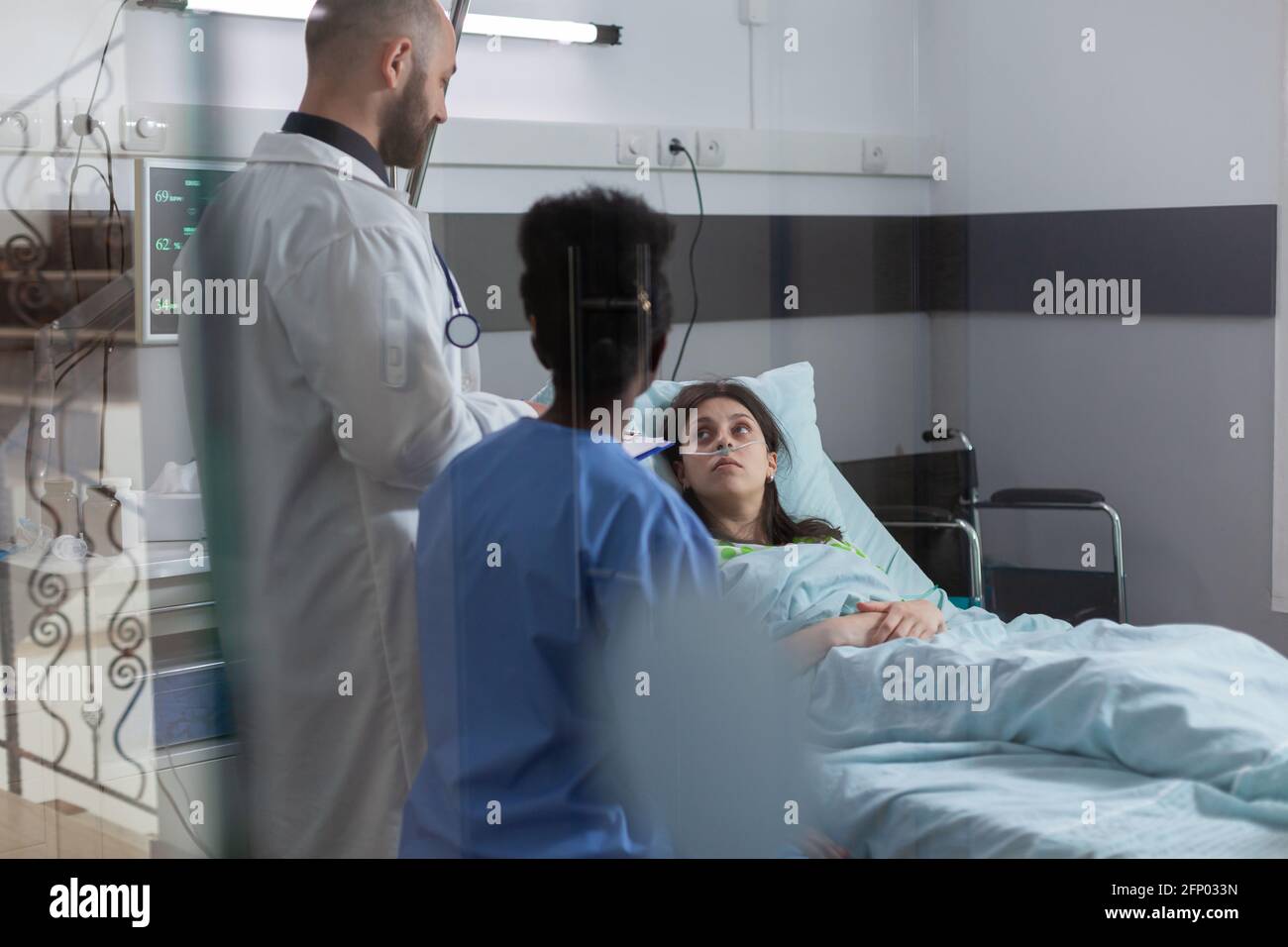 Sick woman patient discussing with medical doctors while resting in bed ...