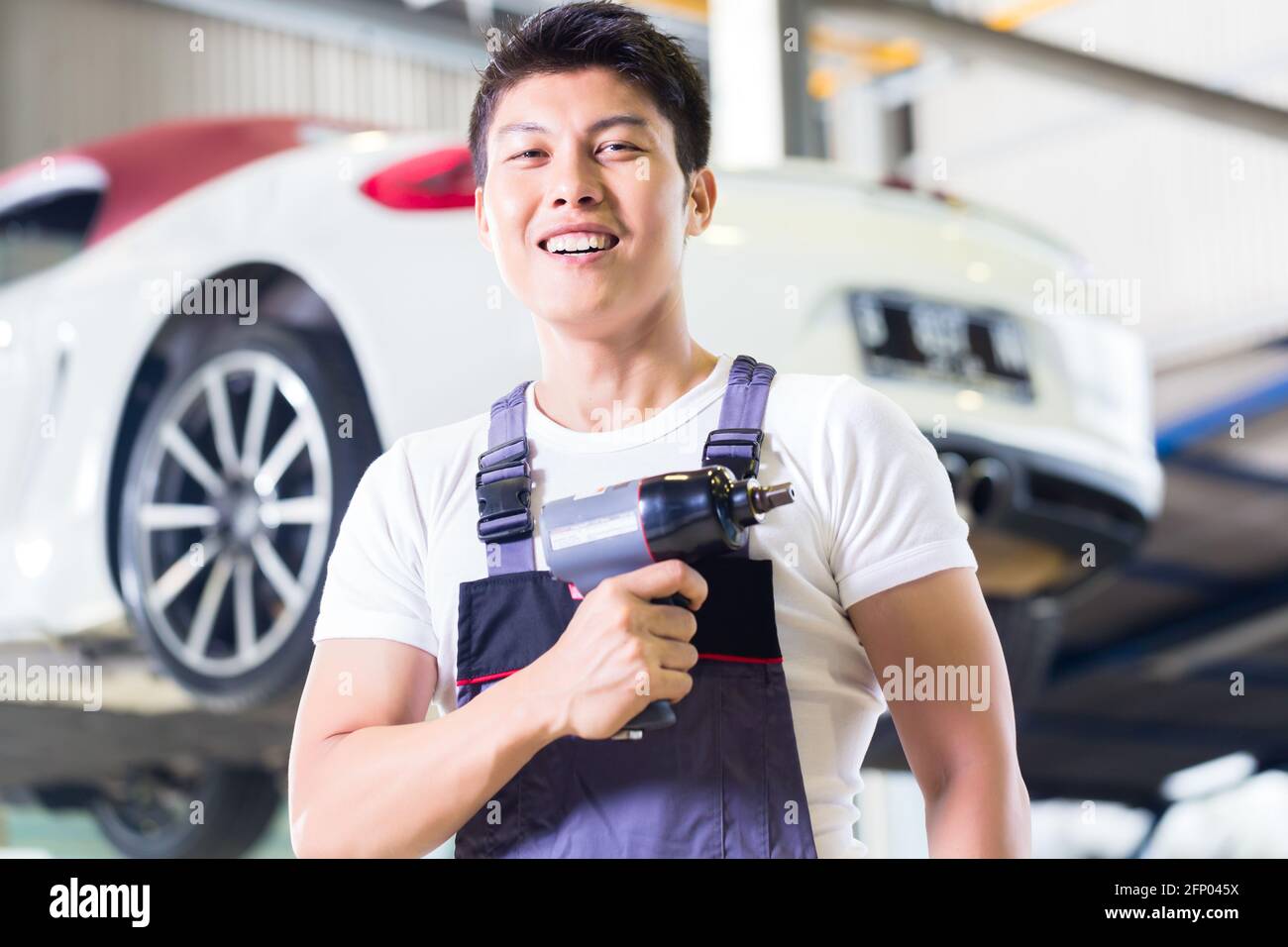 Asian Chinese car mechanic with tool in front of luxury car in auto ...