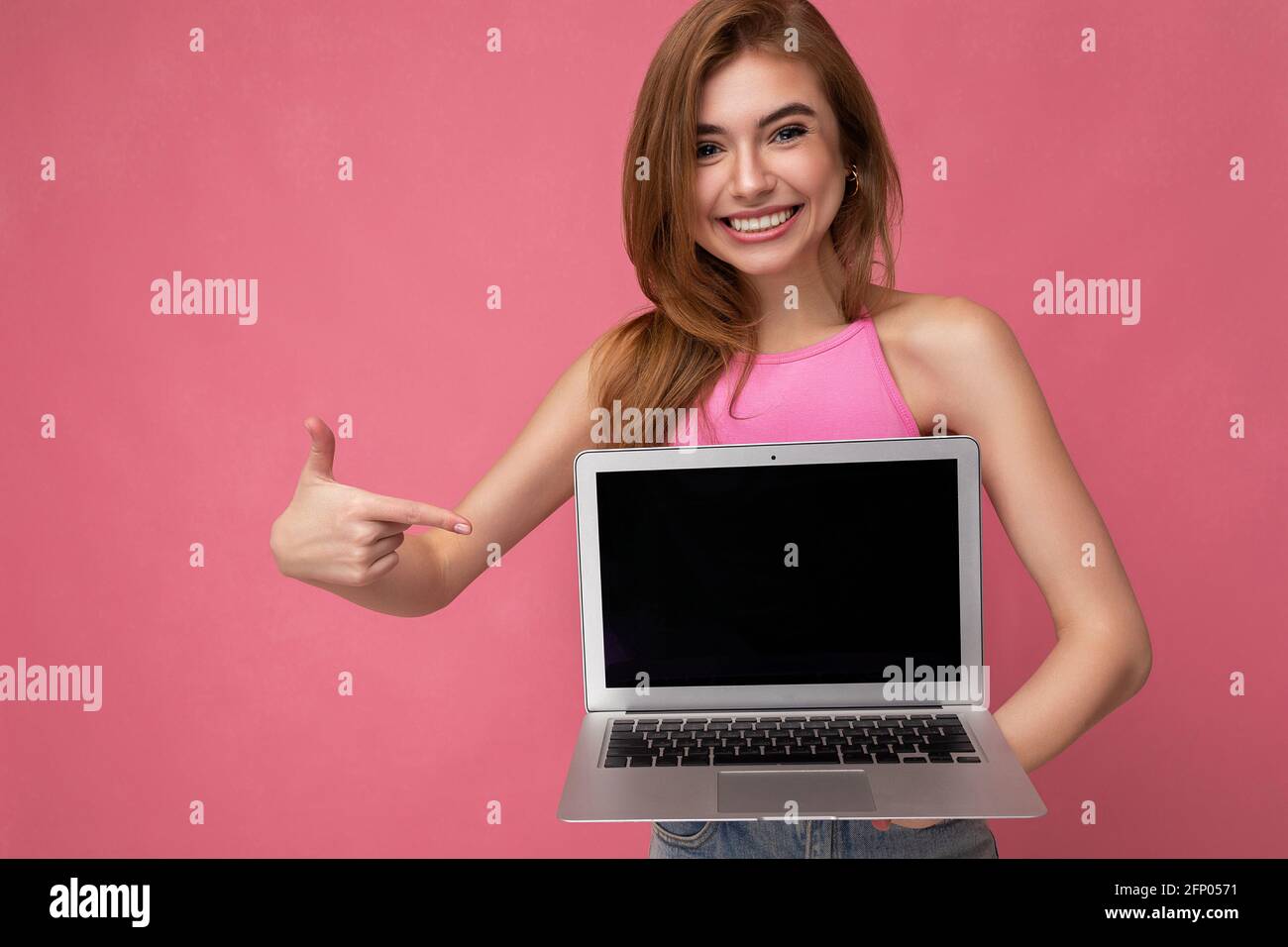 Beautiful young blond woman holding computer laptop with empty monitor ...