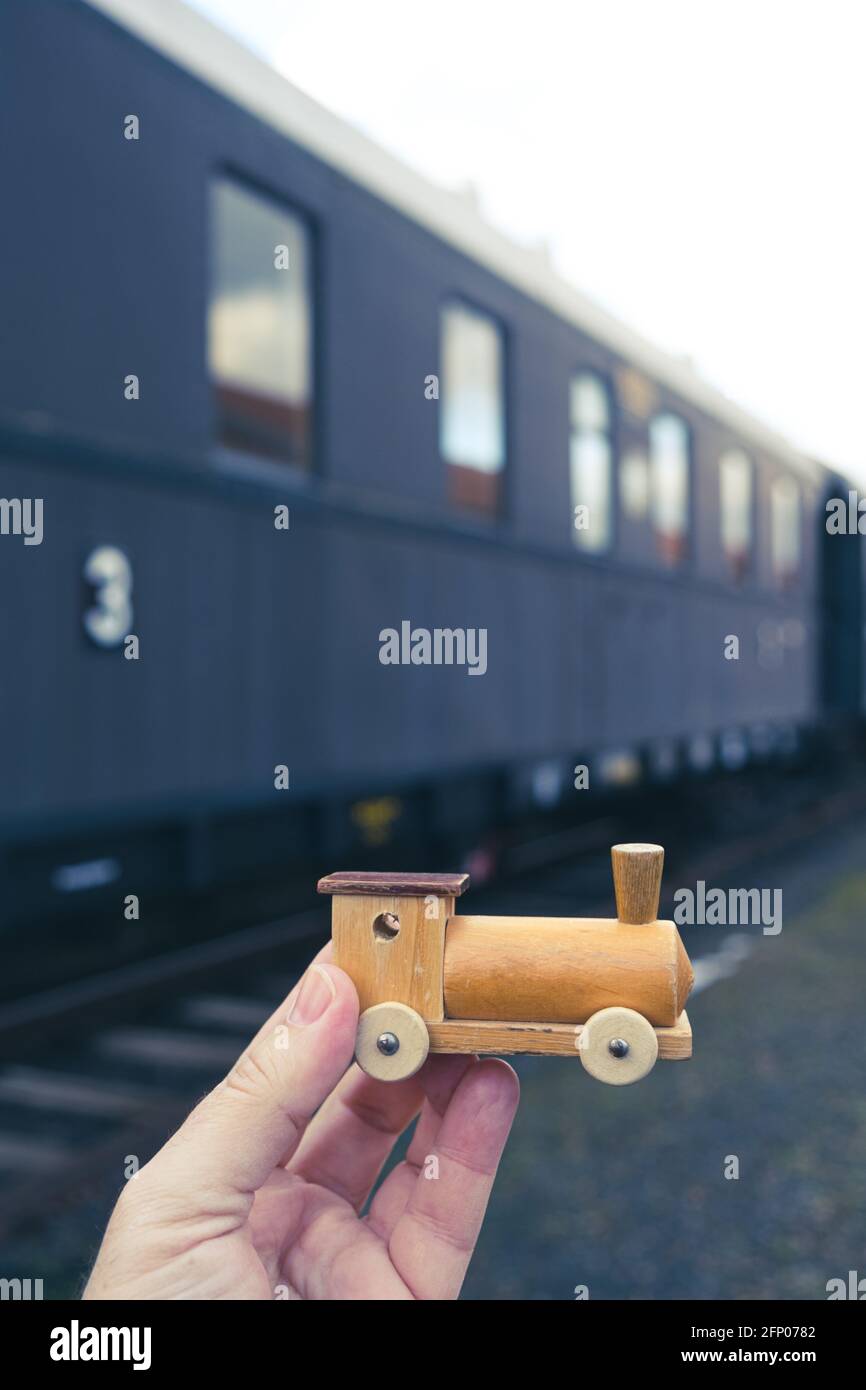 close-up of hand holding toy train in front of historic big train Stock ...