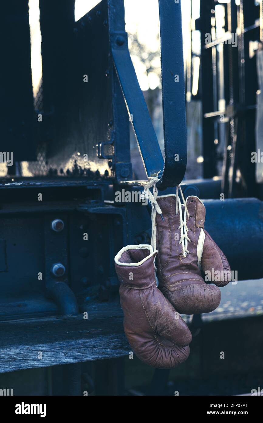 two brown boxing gloves hanging form steel handle Stock Photo - Alamy