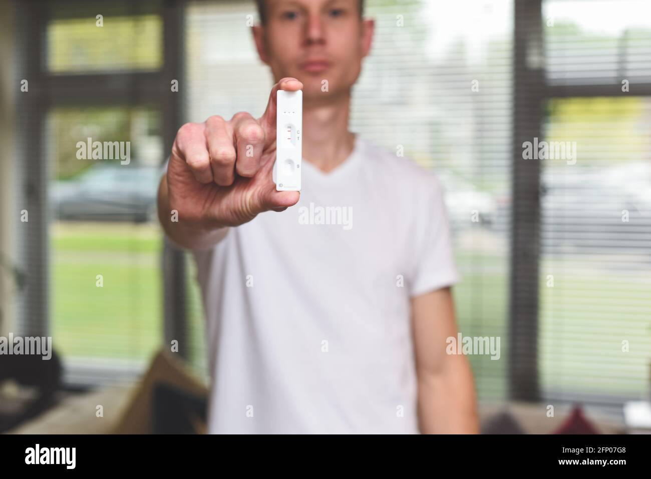Man shows a positive Covid-19 test result from a home testing kit for ...