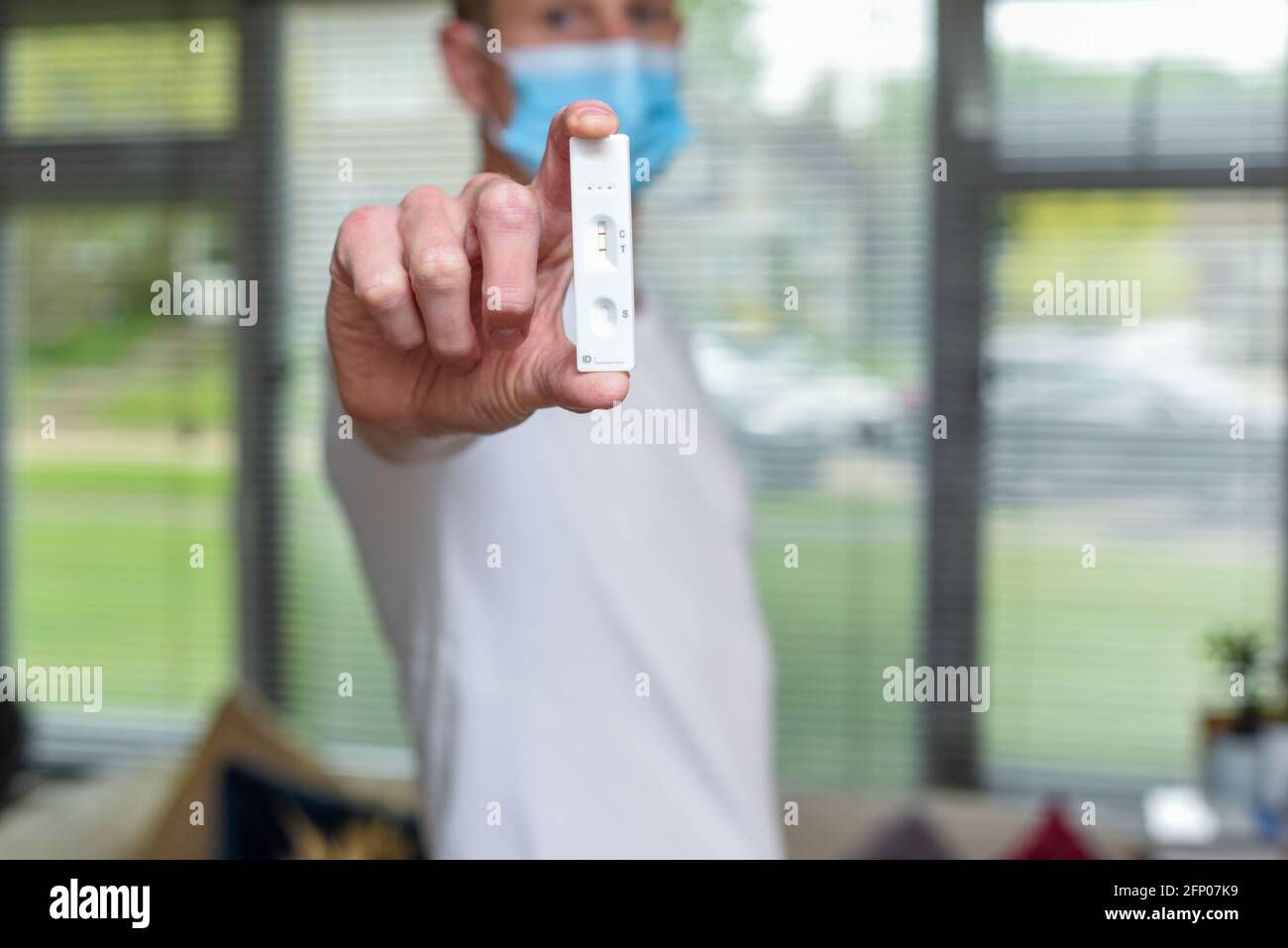 Man shows a positive Covid-19 test result from a home testing kit for ...