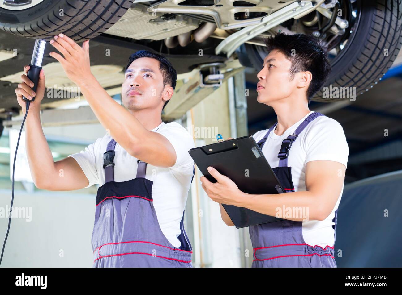 Asian Chinese car mechanic with customer going through the maintenance ...
