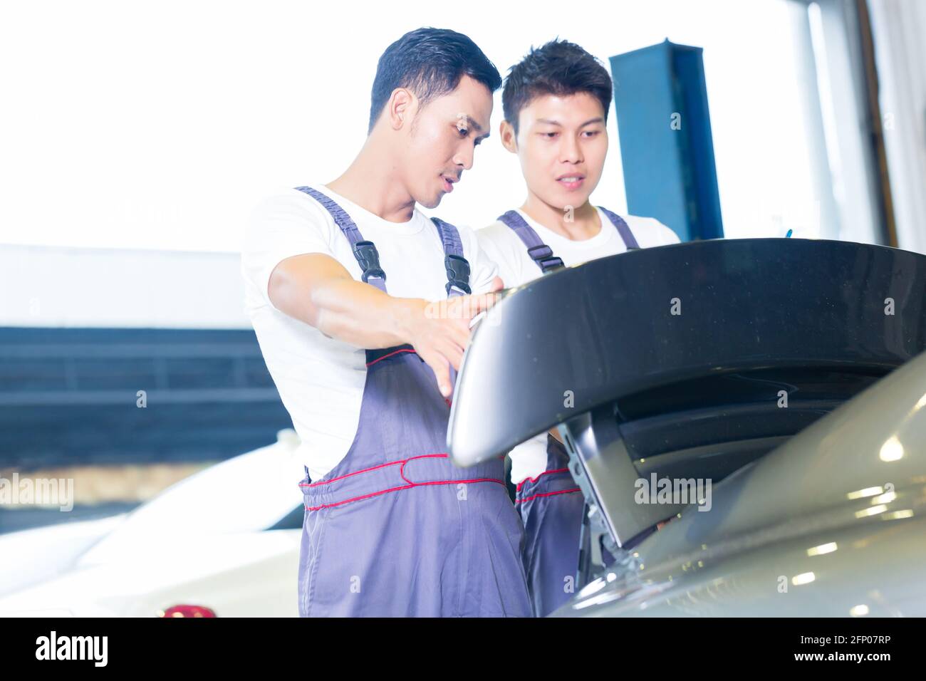 Asian Chinese car mechanics checking auto engine with diagnostics tool ...