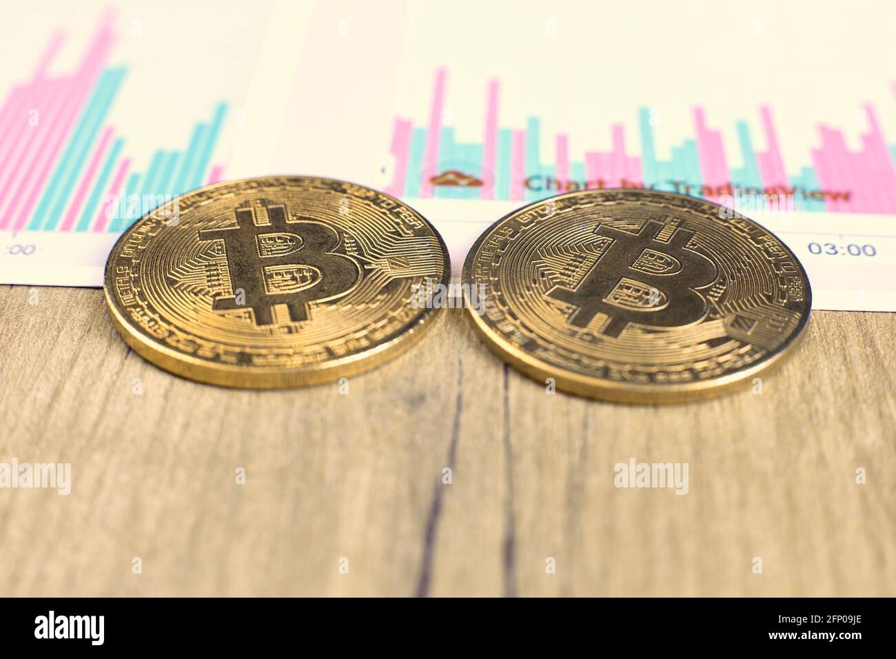 Two gold coins of bitcoin cryptocurrency and charts of changes in ...