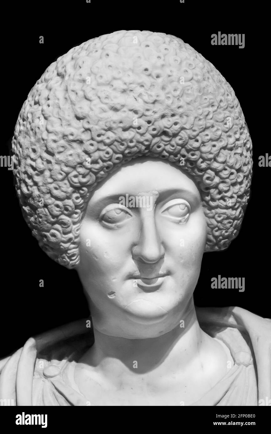 Black and white photo in close-up on face of ancient roman sculpture of woman wearing a big ...