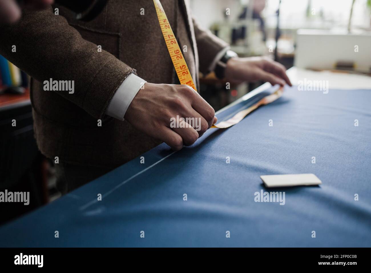 a professional cutter at work. tailor measuring tape Stock Photo - Alamy