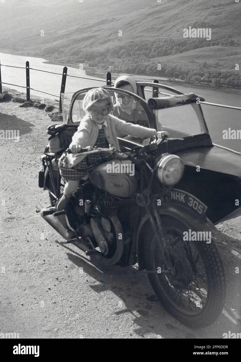 1960, historical, a little girl sitting on a BSA motorbike, with mum ...