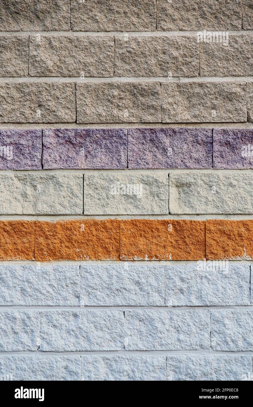 Vertical photograph of a rough cement block wall with gray, purple and ...