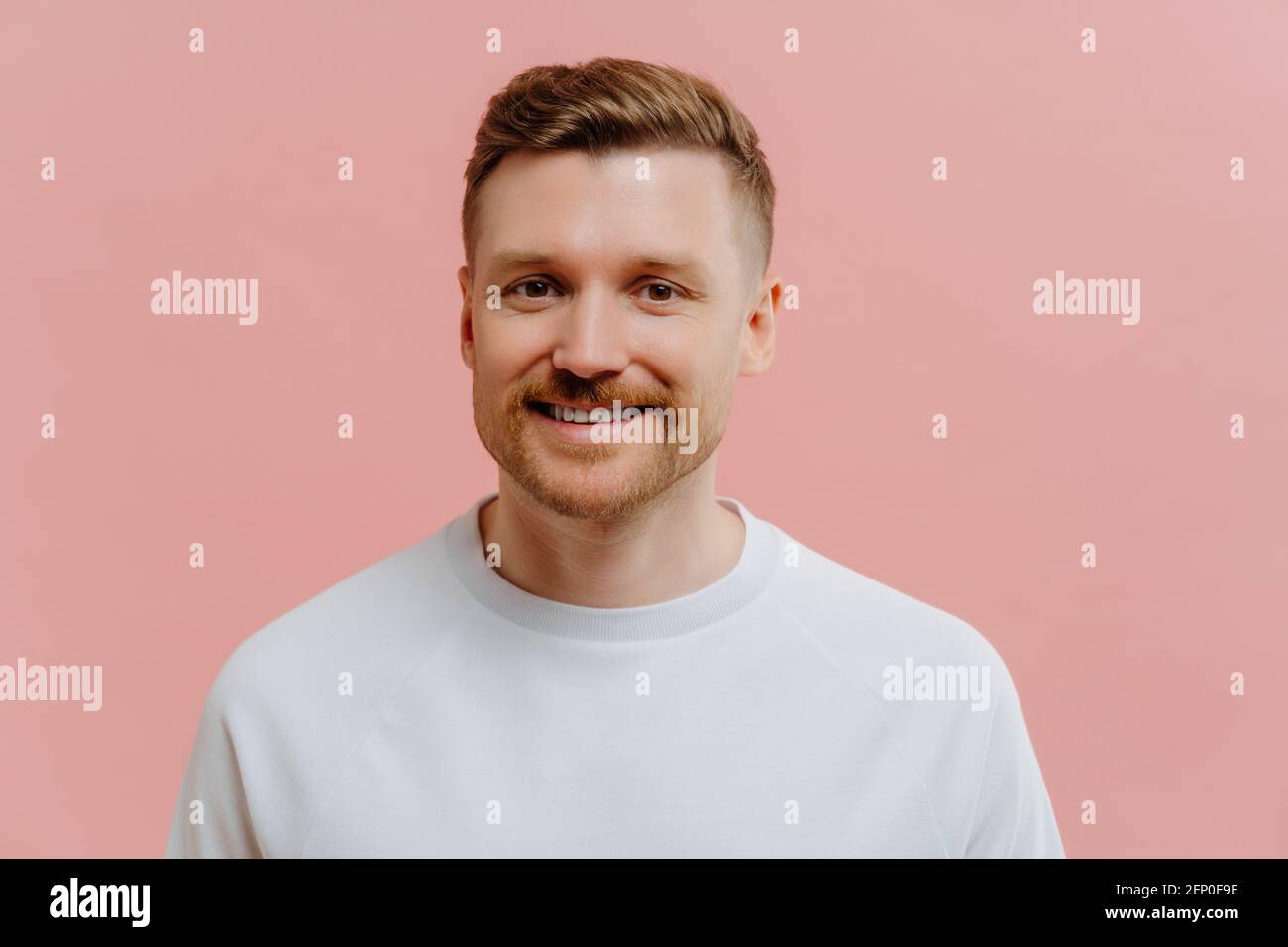 Young positive man smiling at camera in pink studio background Stock ...