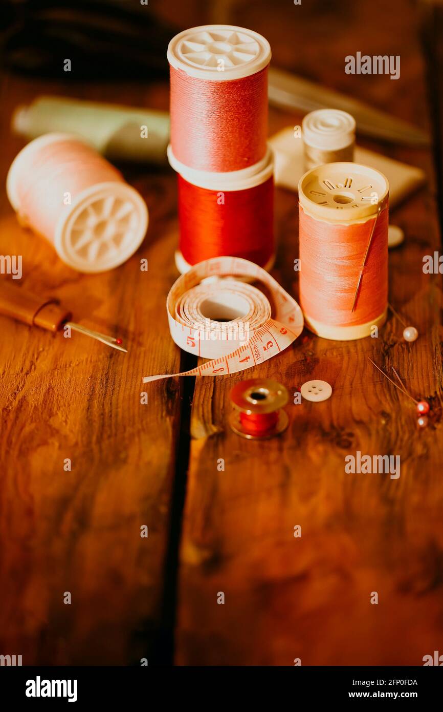 Tape measure and needles placed near threads on lumber table in tailor ...