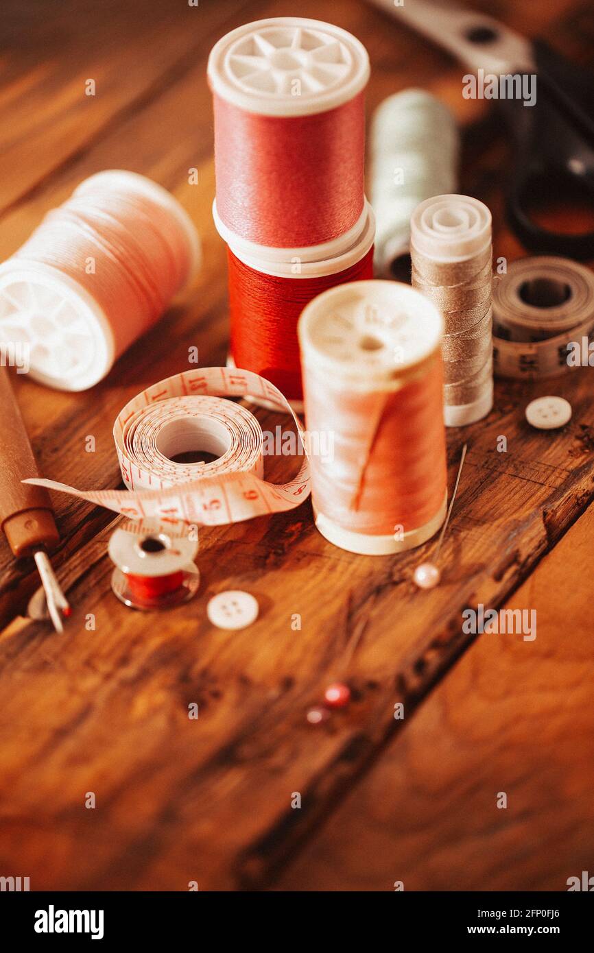 Tape measure and needles placed near threads on lumber table in tailor ...