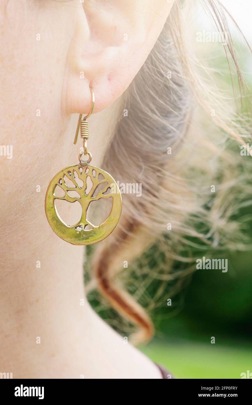Outdoor detail of female ear wearing metal tree shape earring Stock ...