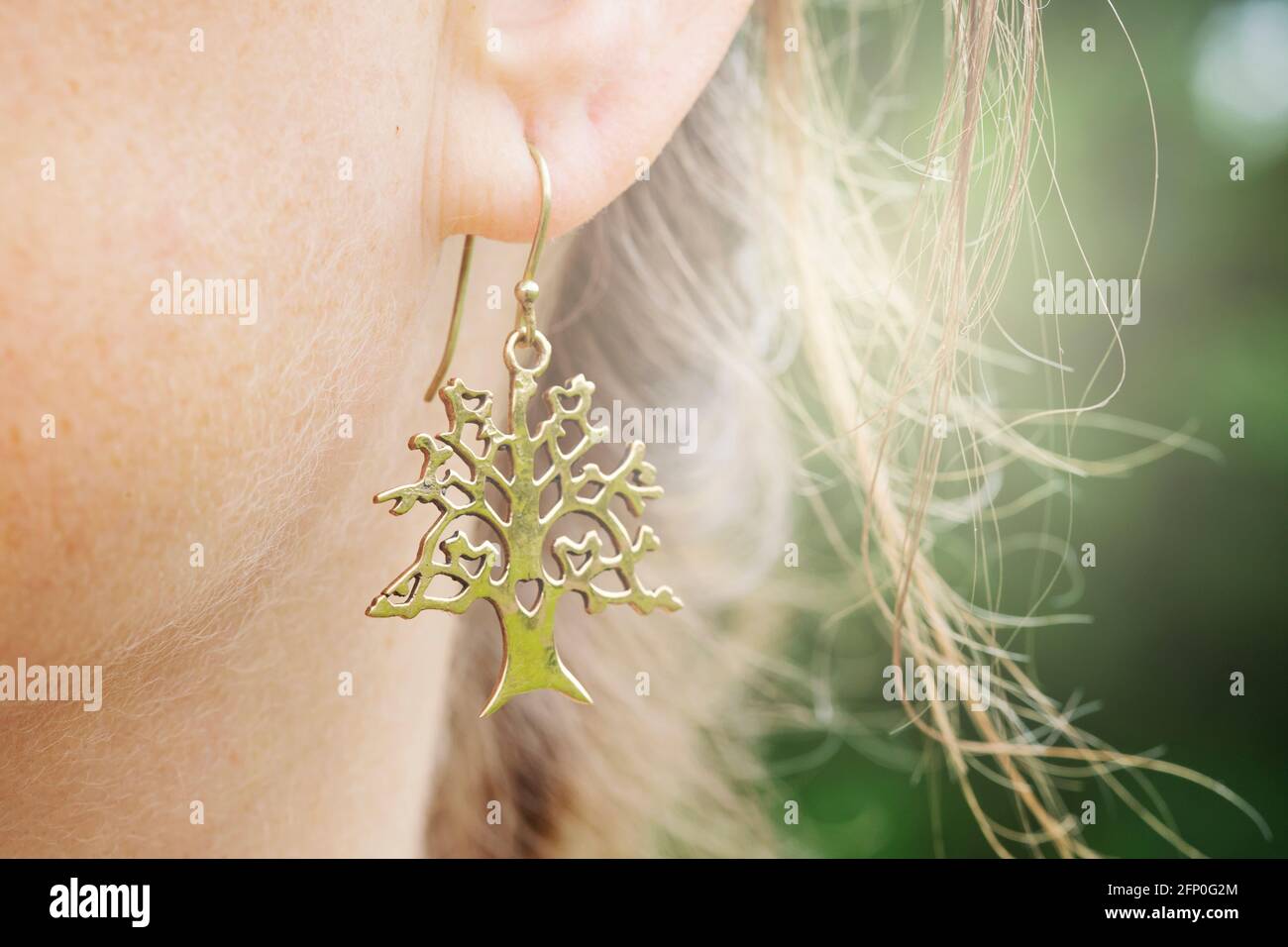 Outdoor detail of female ear wearing metal tree shape earring Stock ...