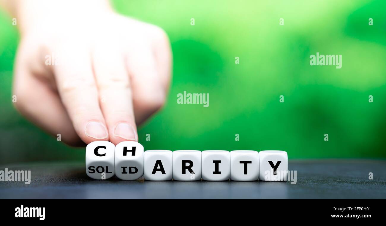 Dice forms the words solidarity and charity Stock Photo - Alamy