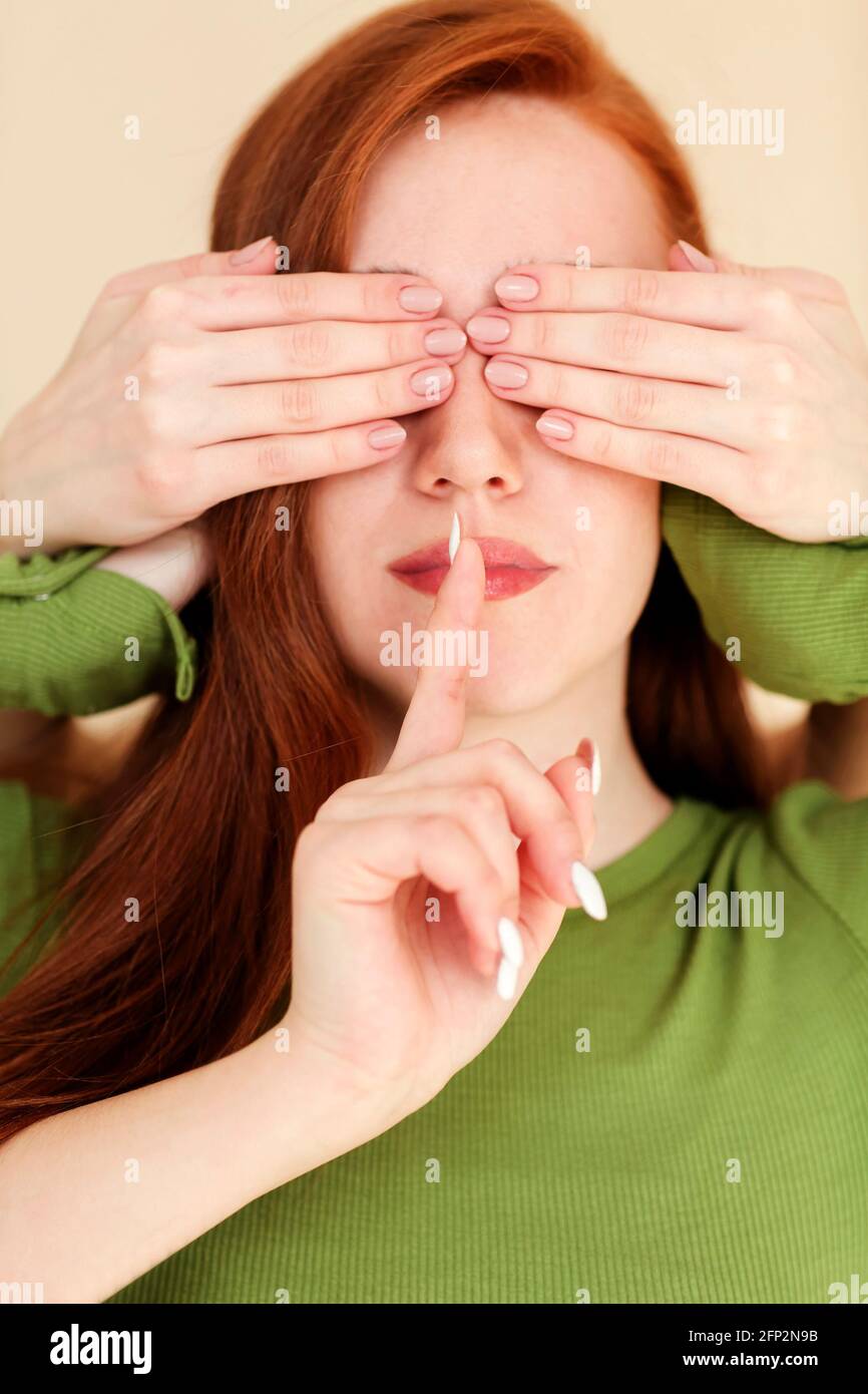 Deaf and blind female with covered eyes keeping finger near lips and ...