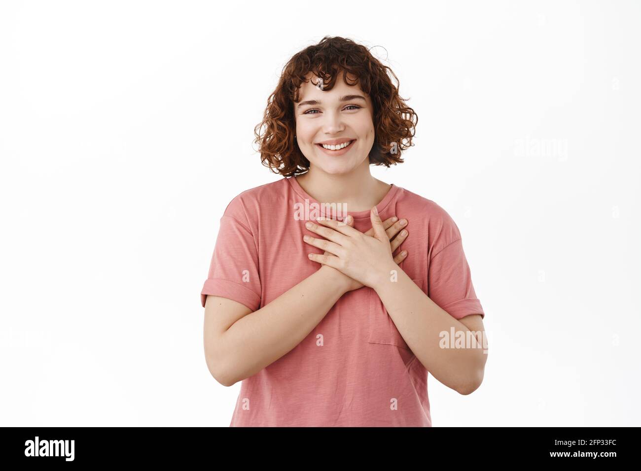 Thankful girl appreciate nice gesture, holding hands on heart, smiling ...