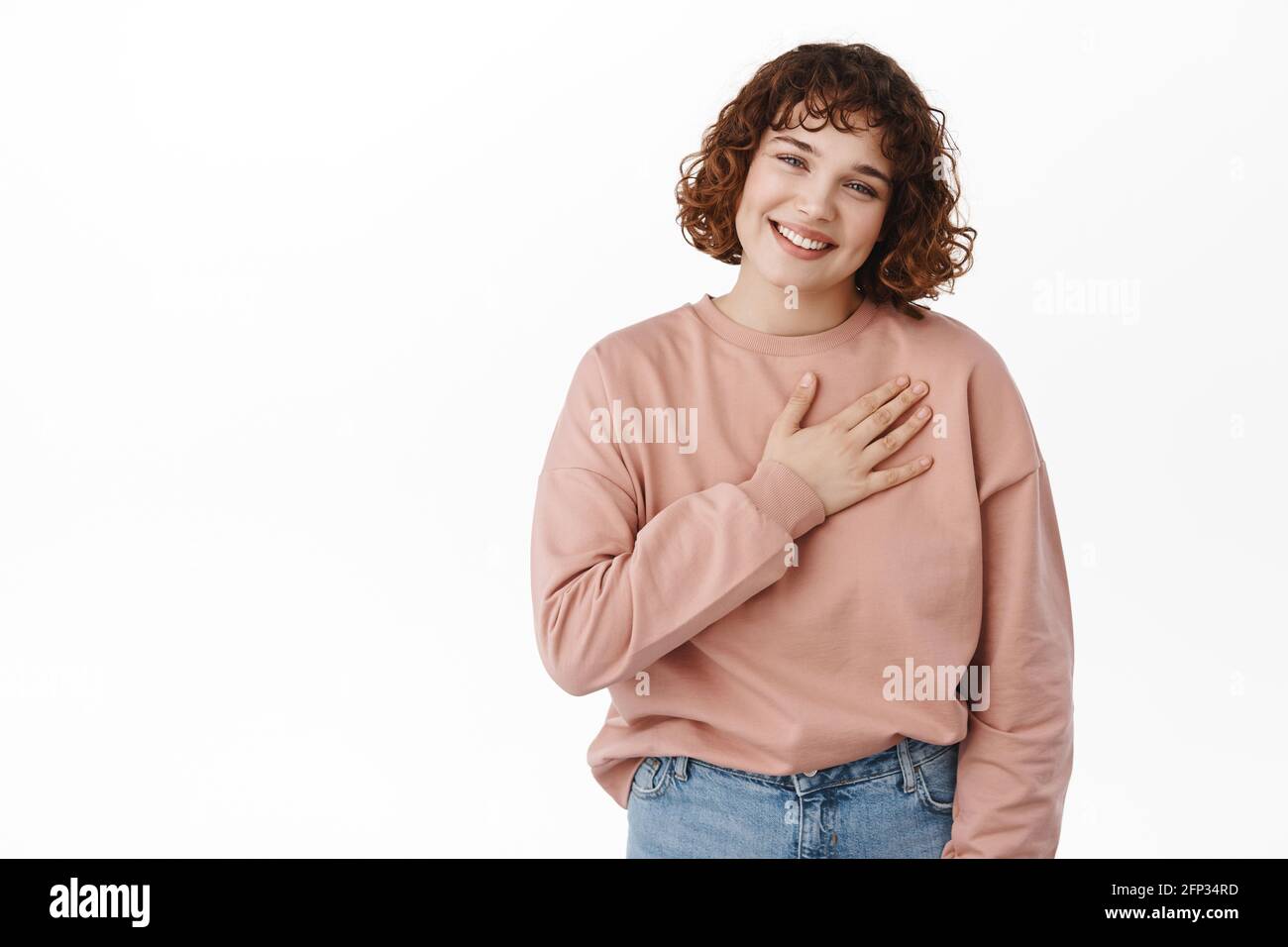 Thankful friendly girl, hold hand on heart and smile touched ...