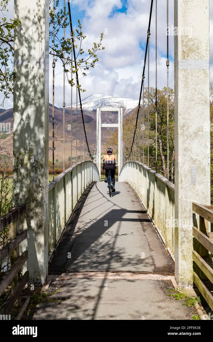 Female cyclist crossing the suspension bridge at Portinscale close to ...
