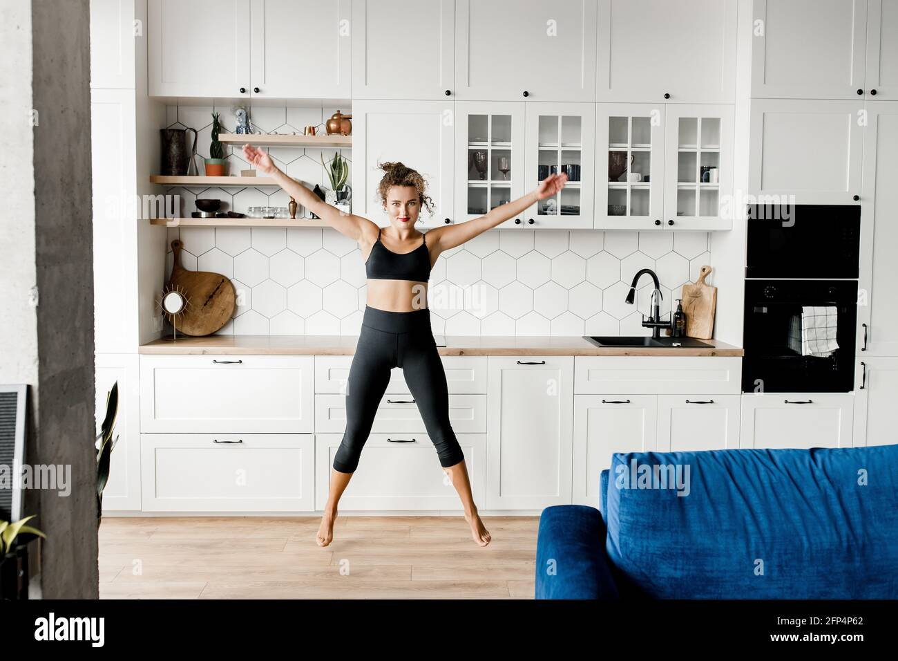 Going crazy. Funny positive young female jumping at modern kitchen in ...