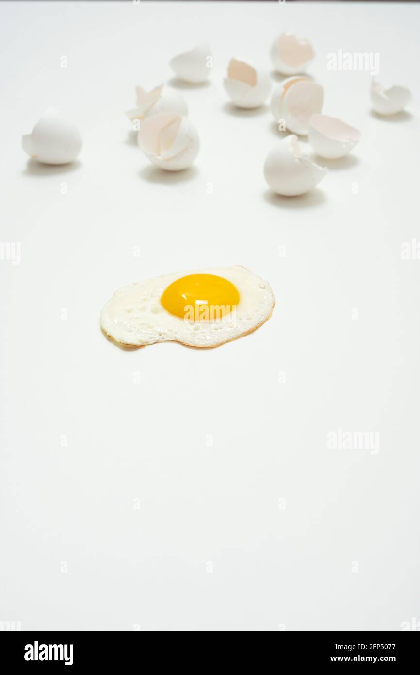 scrambled eggs with whole yolk and broken shells on white background ...