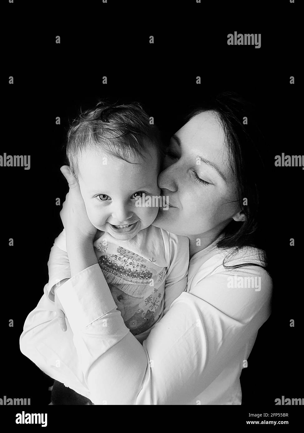 Black And White Portrait Of Mother Hugging And Kissing Smiling Girl