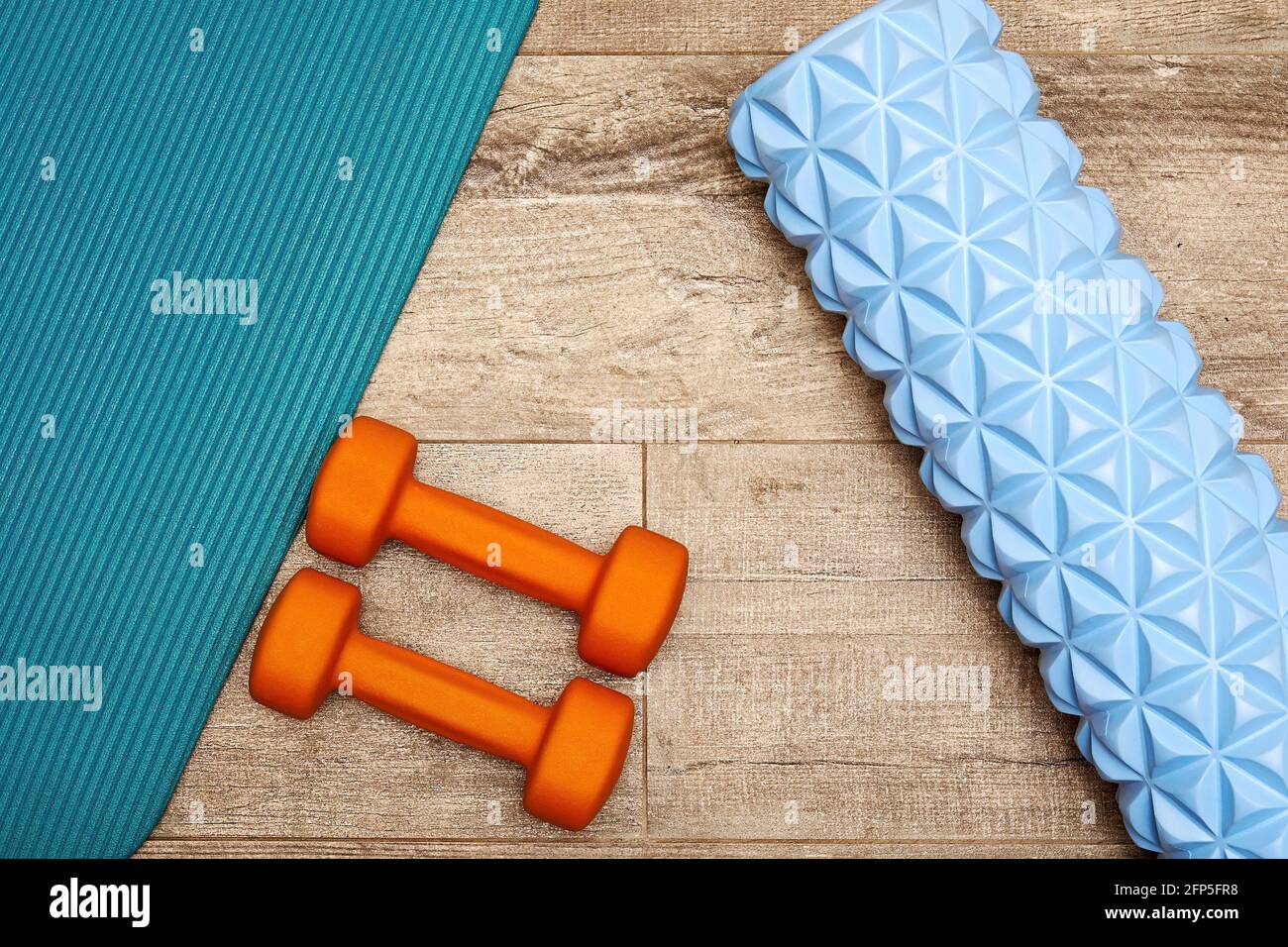 Colourful fitness dumbbell and roller on the sports mat in the gym ...