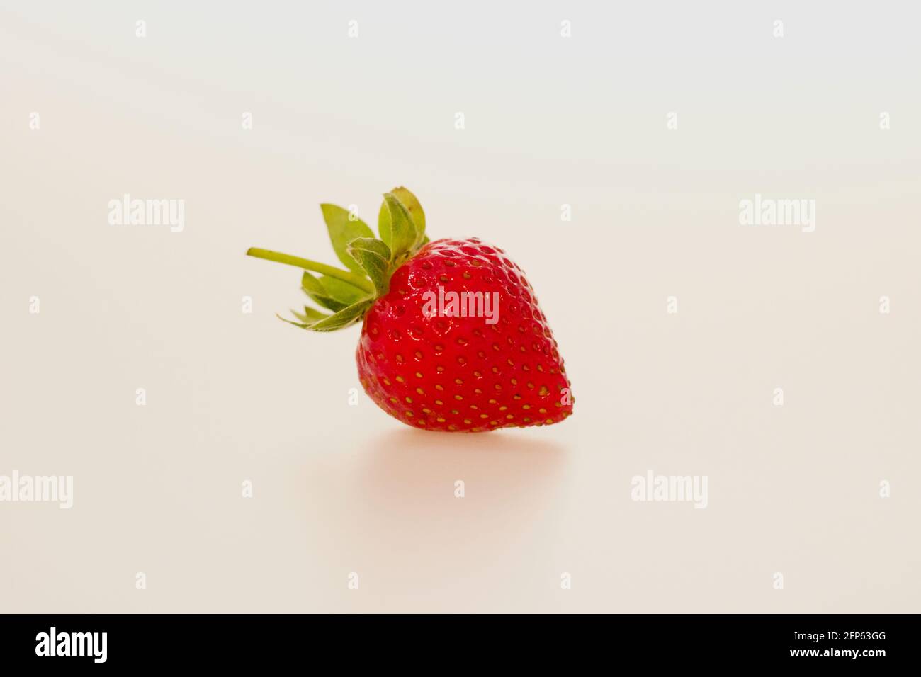Single strawberry against plain white background with space for copy ...