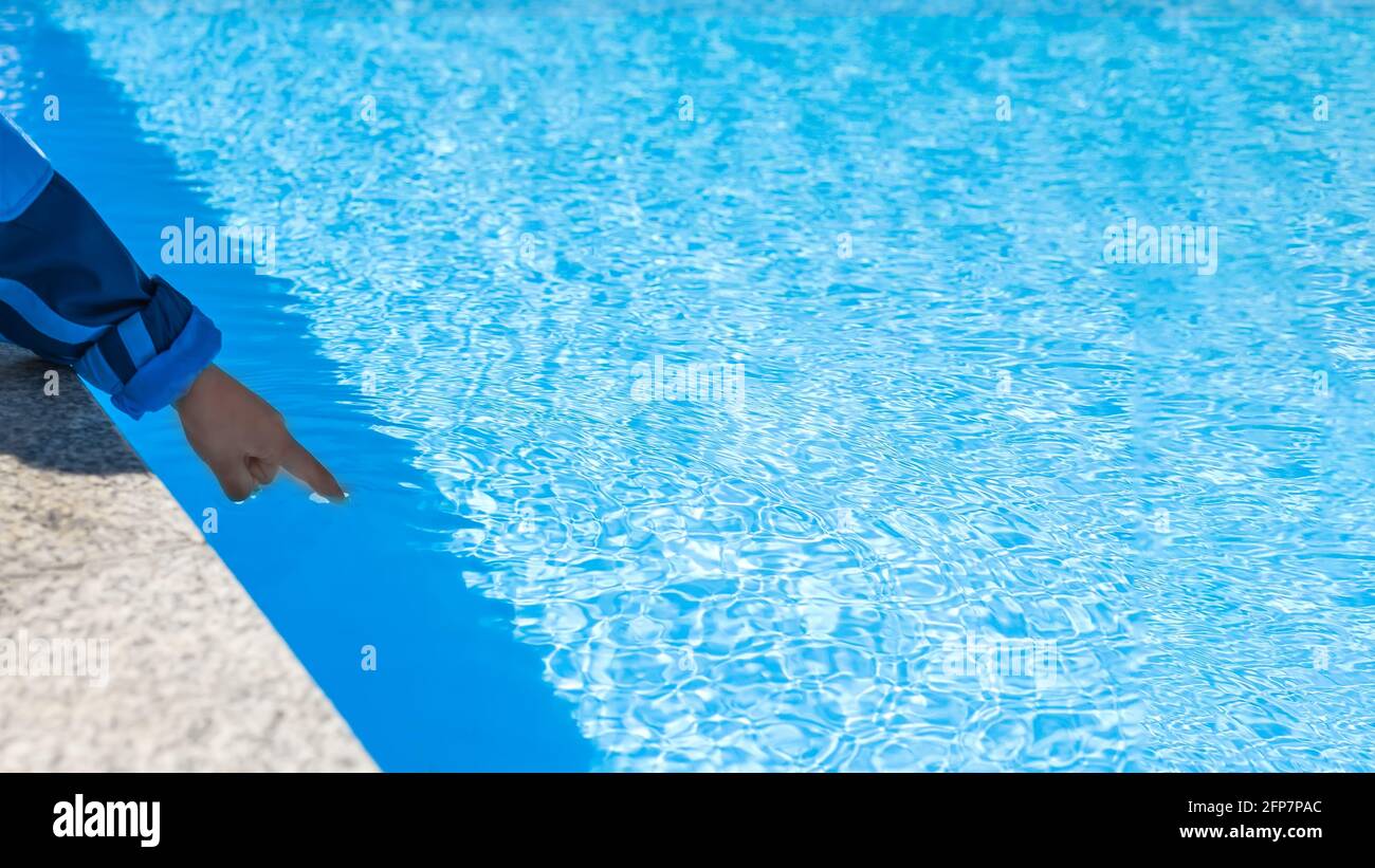 a child's hand touches the blue water in the pool , Swimming pool and ...
