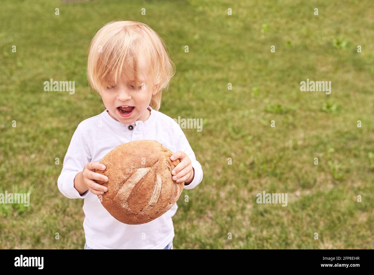 Child holds and bite round bread. Healthy food Stock Photo - Alamy