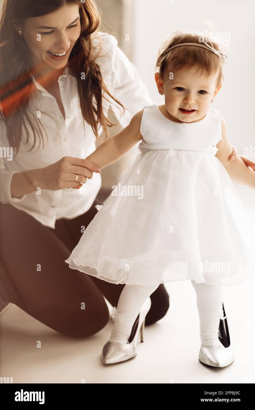 Adorable cute toddler doing first steps, smiling, holding mom's hands ...