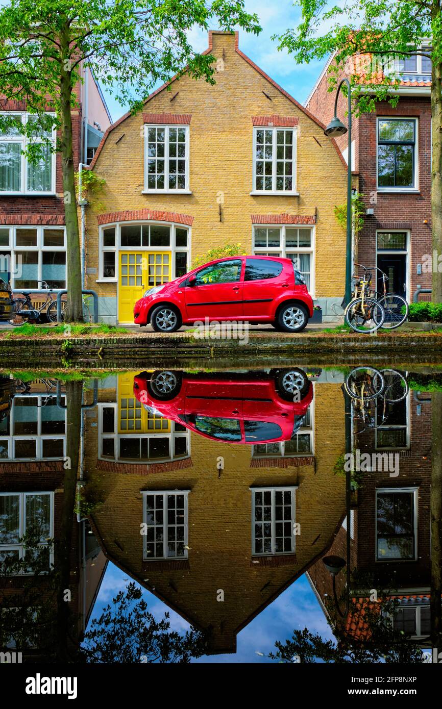 Red car on canal embankment in street of Delft. Delft, Netherlands ...