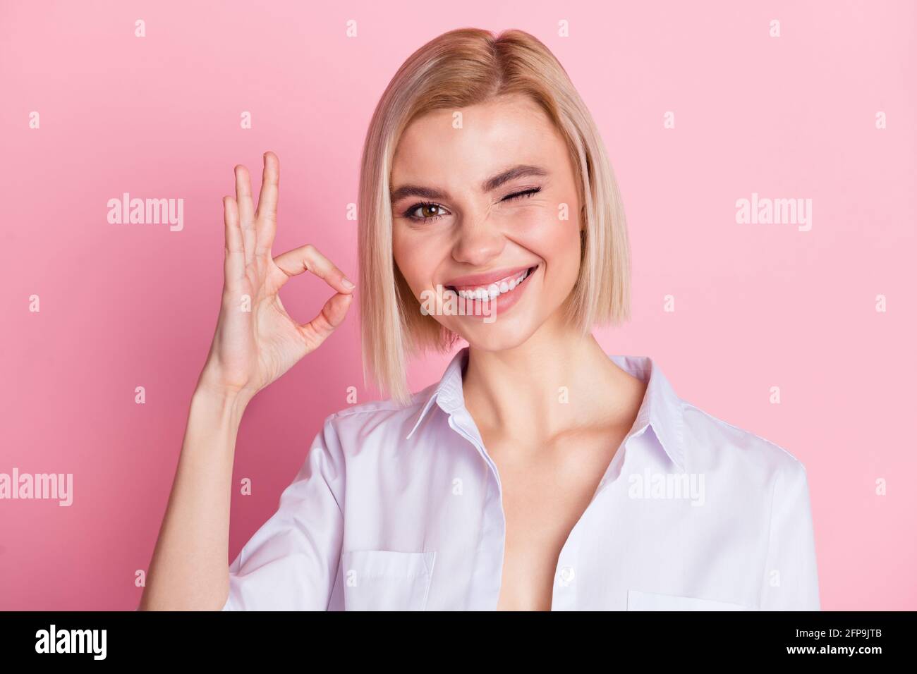Photo of cheerful positive young charming woman make okay sign wink eye ...