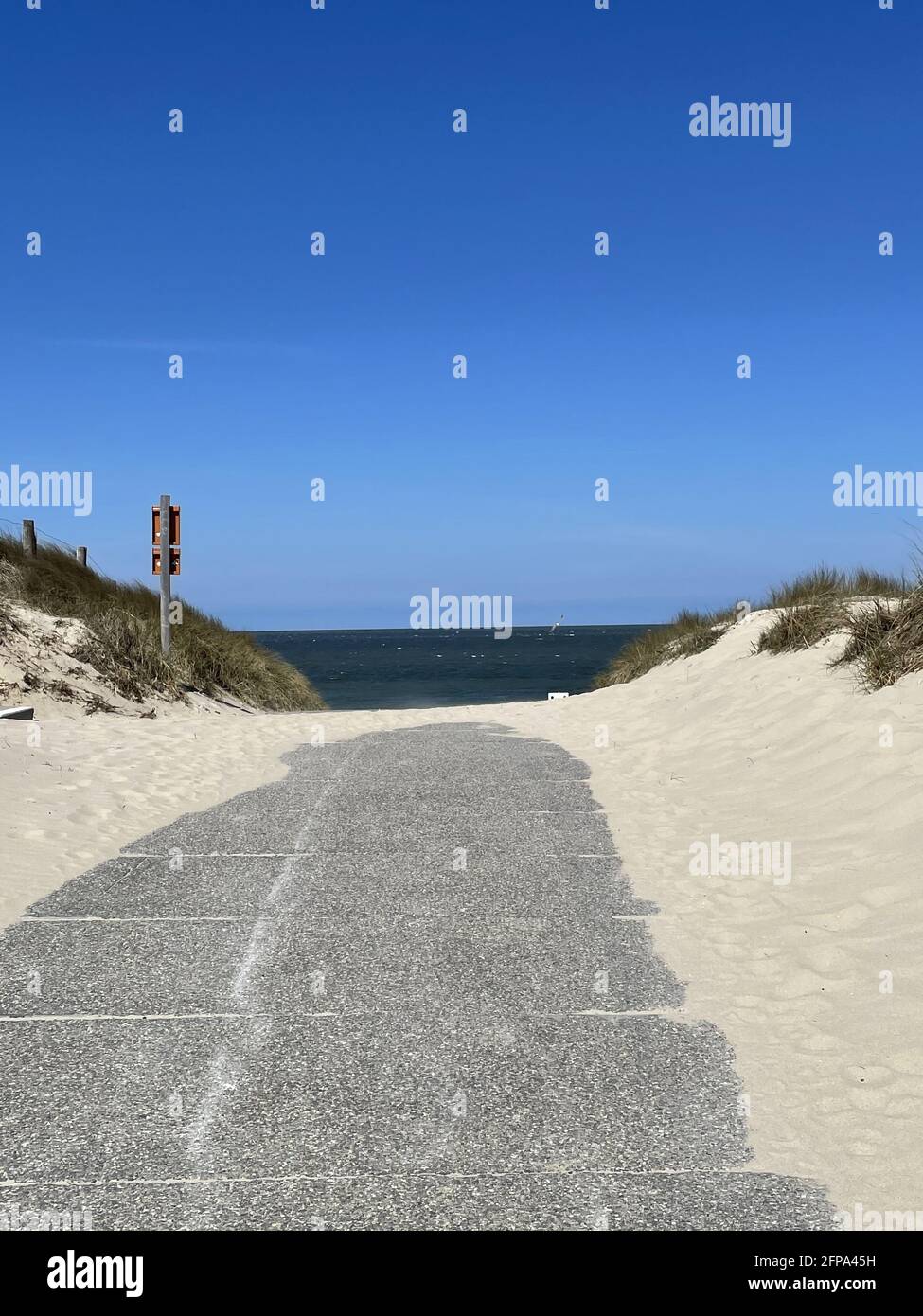 Closeup shot of a path leads to the ocean in the blue sky background ...