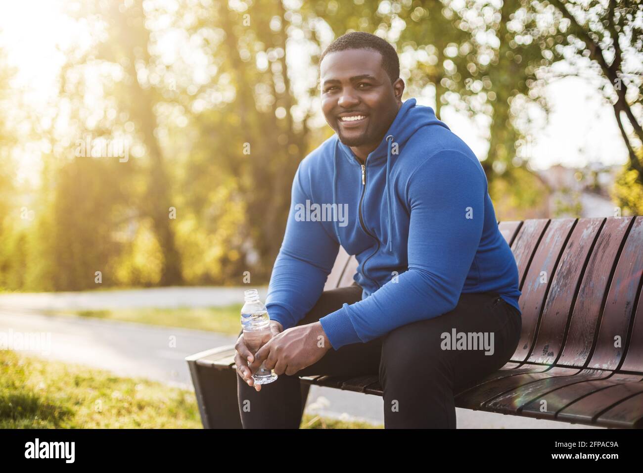 Man resting on bench after exercise and drinking water Stock Photo - Alamy