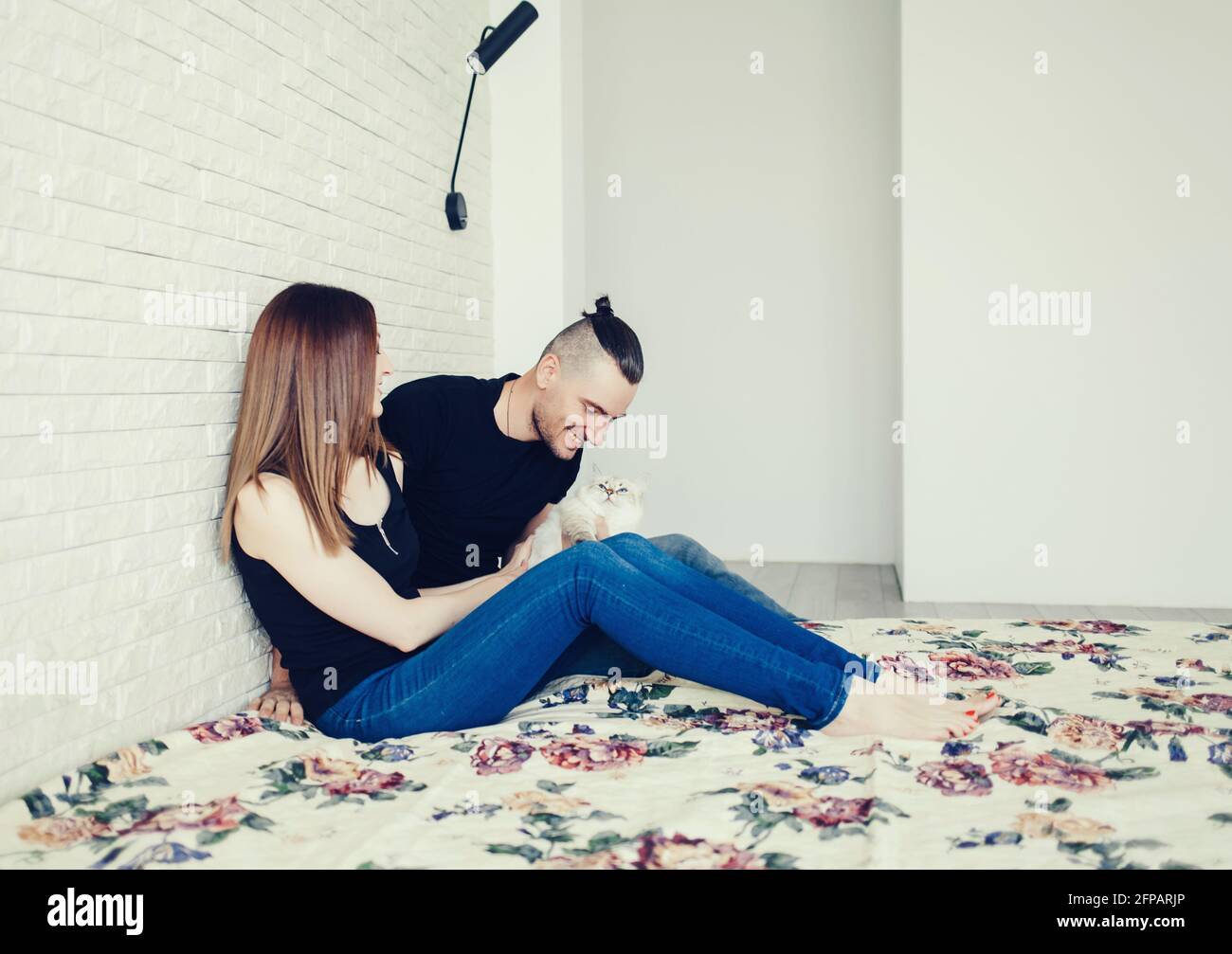 Happy loving couple sitting with cat on bed. Family concept Stock Photo ...
