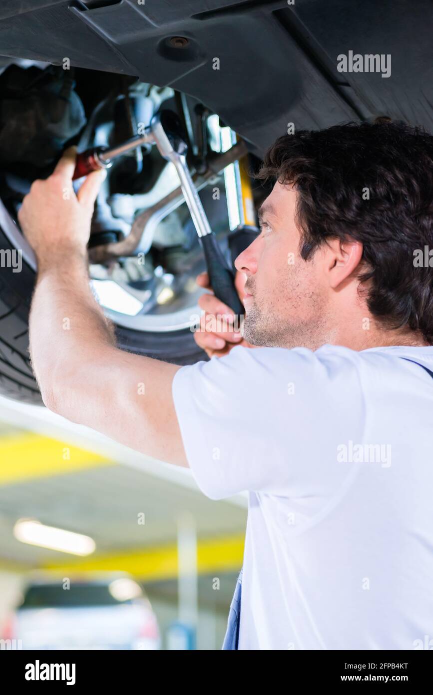 Mechanic working in car workshop on wheel Stock Photo - Alamy