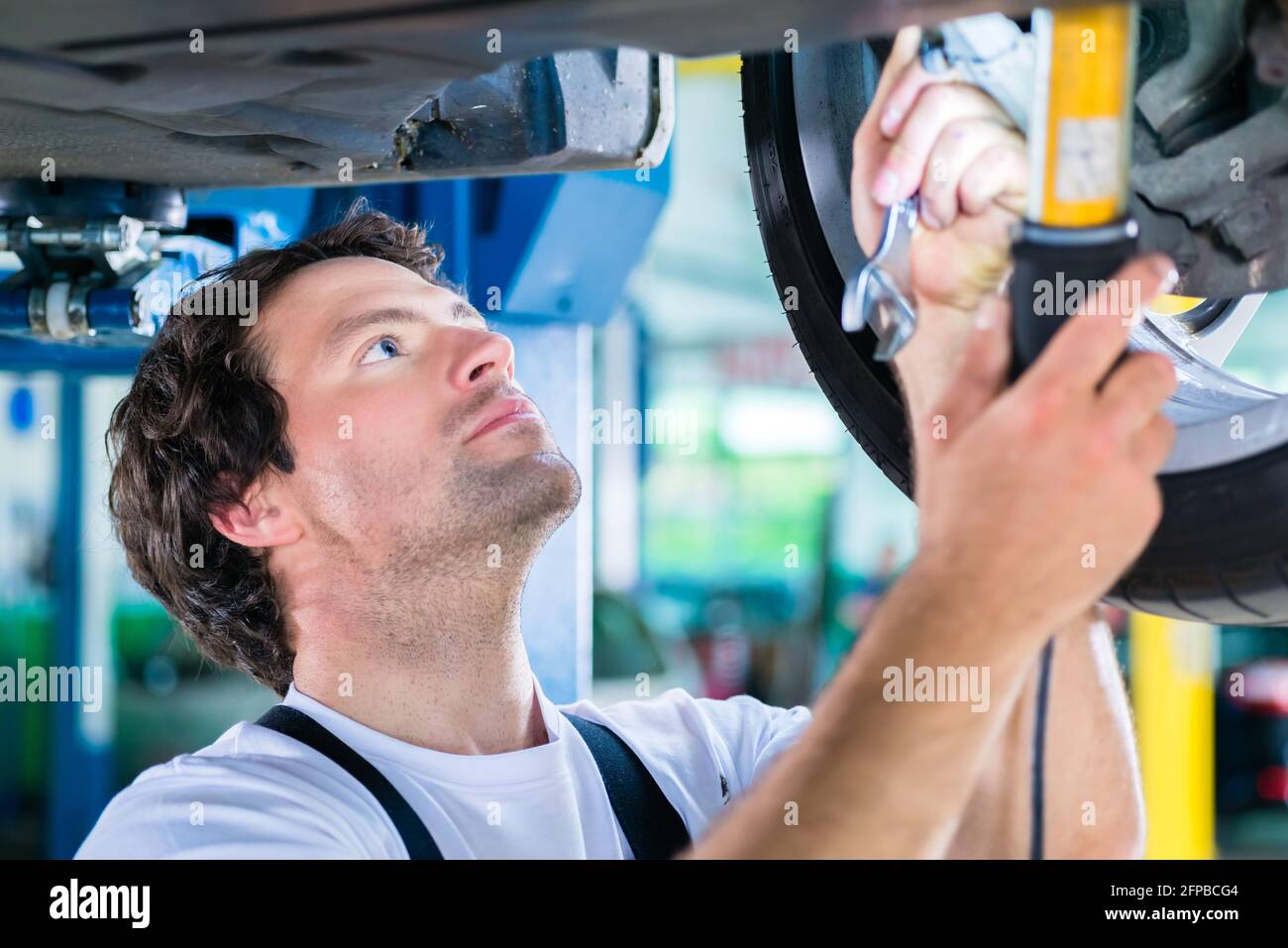 Car mechanic working in car workshop on wheel Stock Photo - Alamy