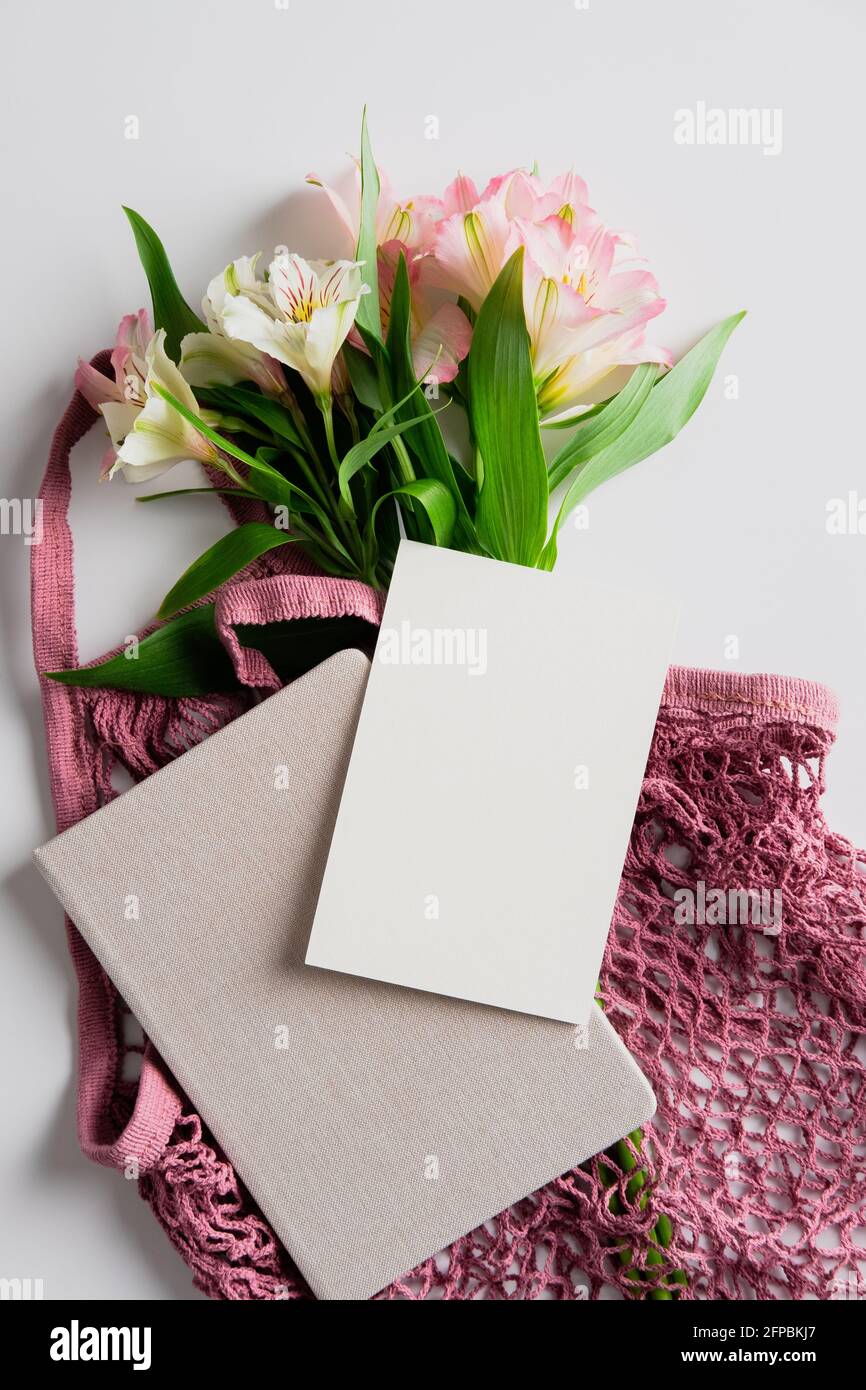 String grocery bag with flowers, paper notebook and blank paper card on ...