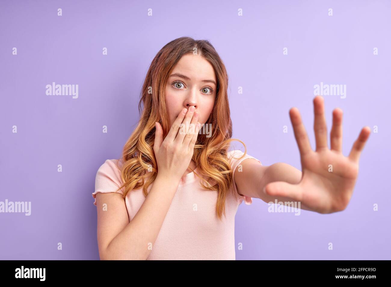Young girl over isolated purple background scared with arms up like ...