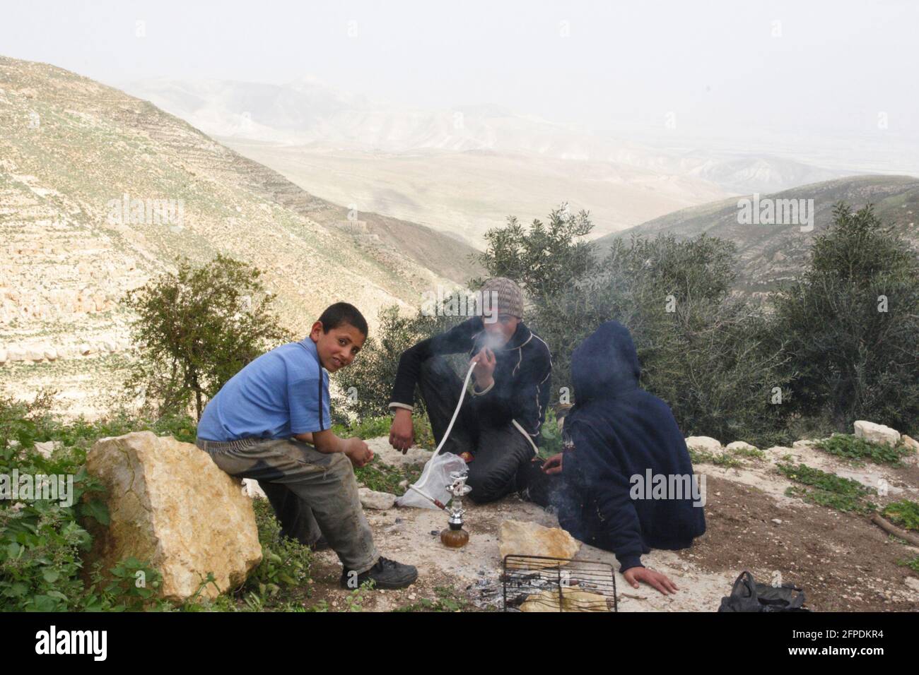 Beduin or Arab nomad sits with his sons, one of them smiling, he ...