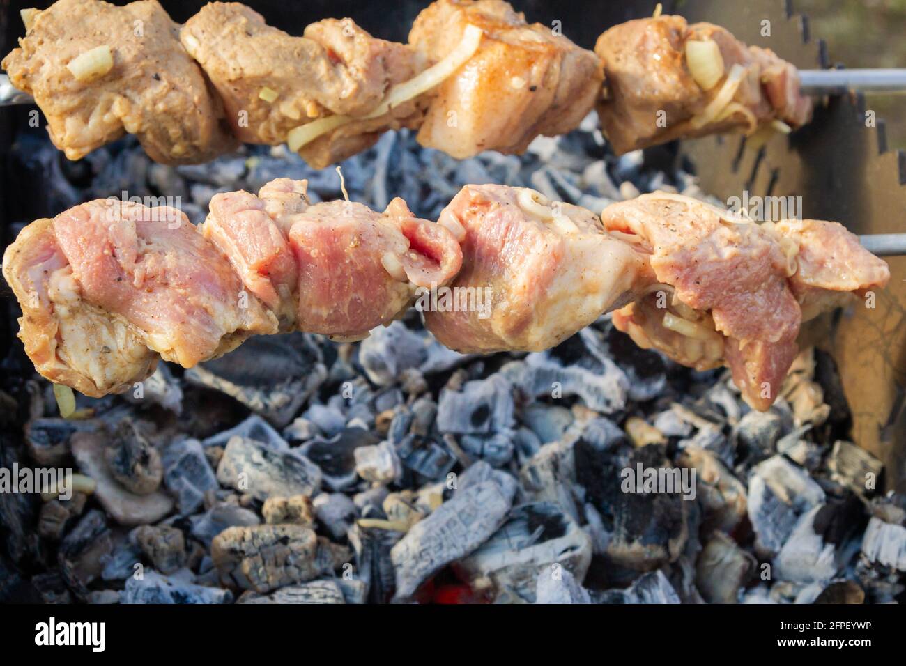 Shish Kebab made from pieces of pork is cooked on skewers on the grill ...