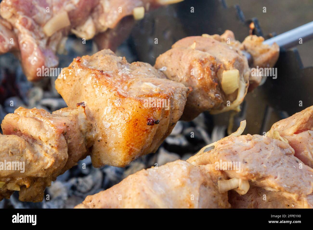Shish Kebab made from pieces of pork is cooked on skewers on the grill ...