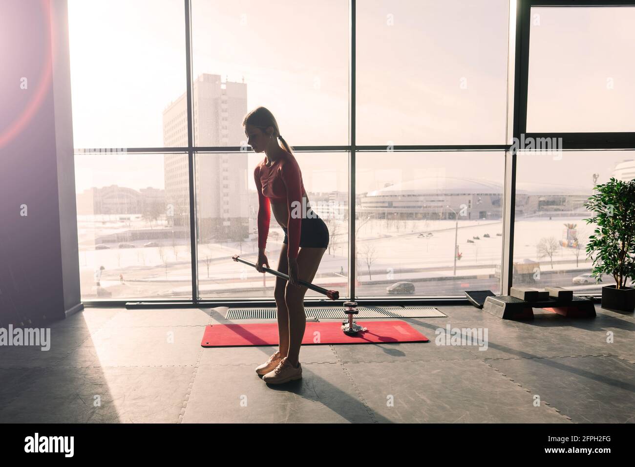 Beautiful muscular woman doing exercise with gymnastic stick in a gym ...