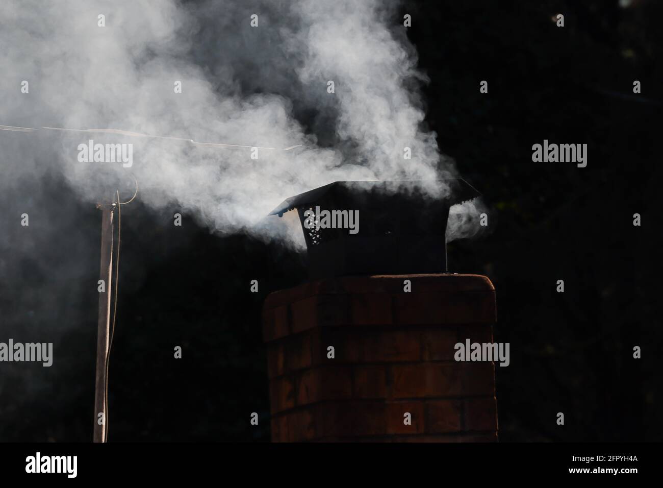 White pillar of smoke rising from a red brick chimney in residential ...